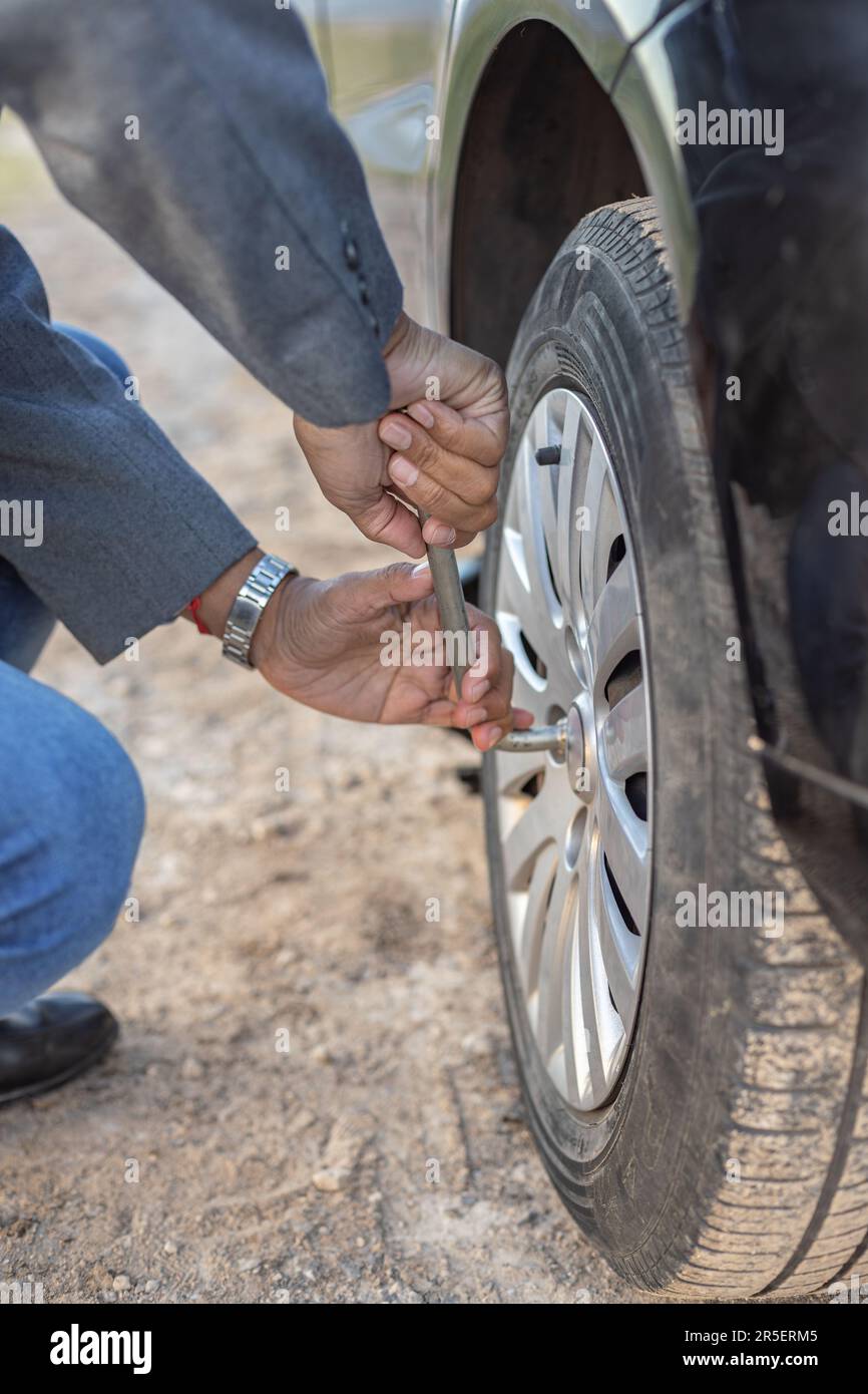 Detail of the hands of a Latino man loosening a nut to change a flat ...