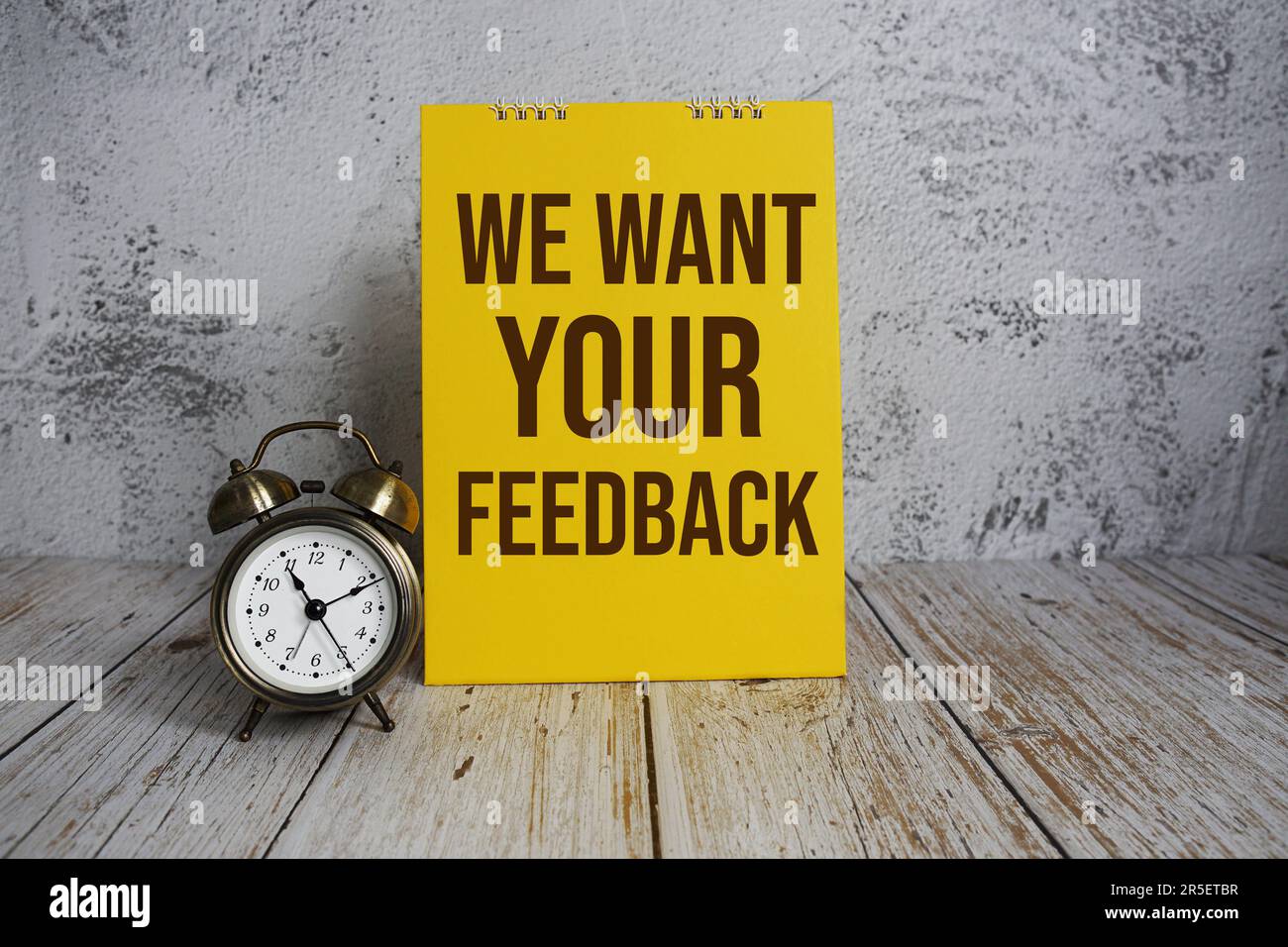 We want your feedback text message and alarm clock on wooden background ...