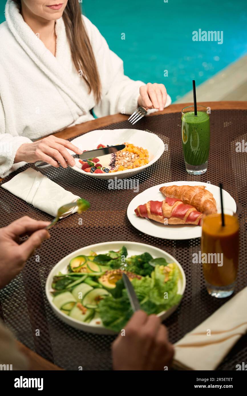 Two people eating by swimming pool in wellness center Stock Photo - Alamy