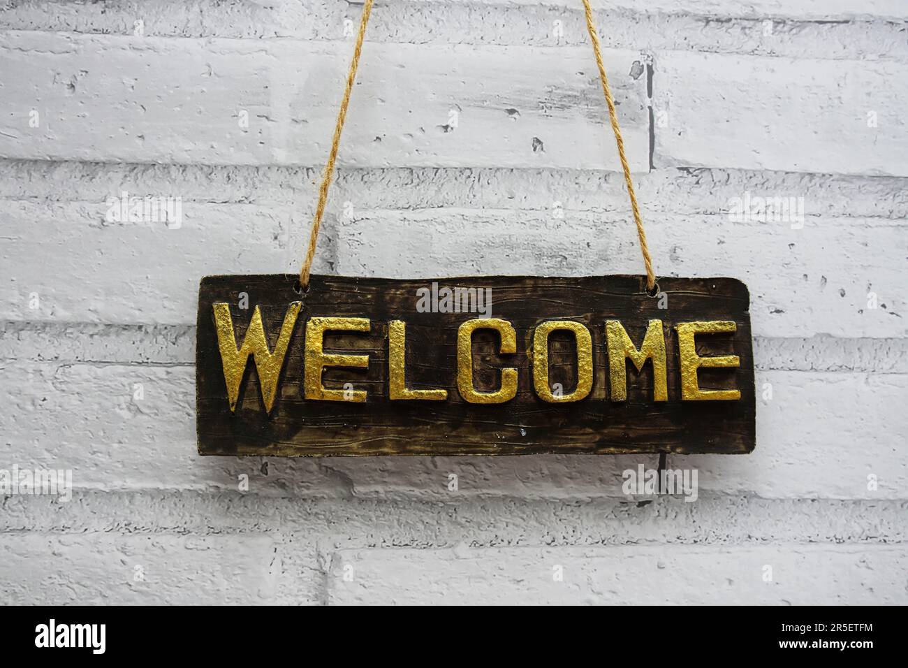 Welcome sign hanging with rope on white brick wall background Stock ...