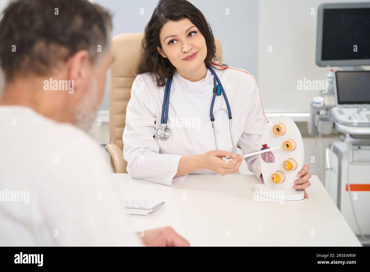Woman cardiologist showing model of heart to man Stock Photo - Alamy