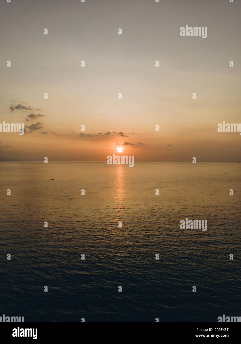 The sun sets over a peaceful body of water, painting the sky in ...