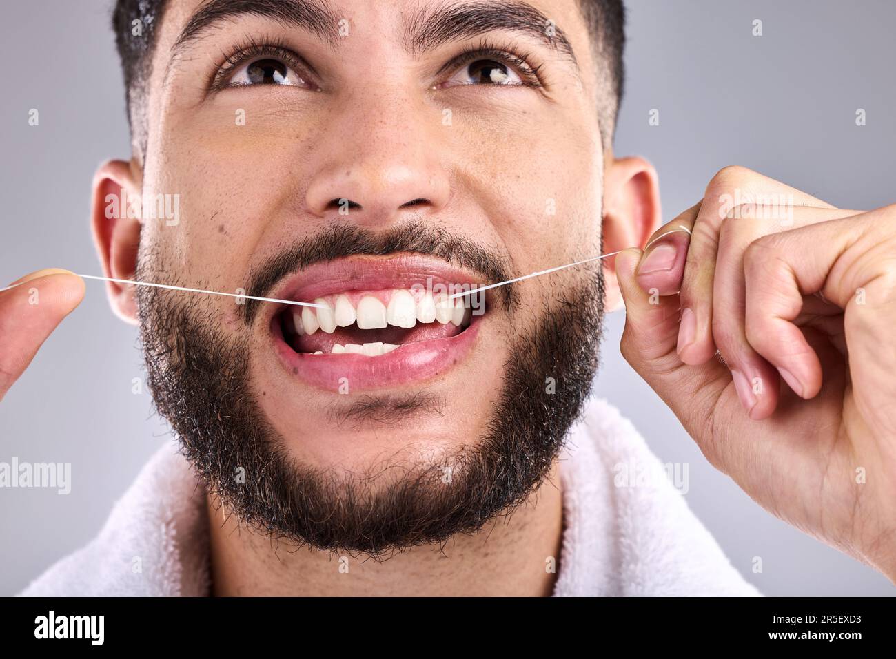Face, dental and man floss teeth in studio isolated on a white background. Tooth, flossing ...