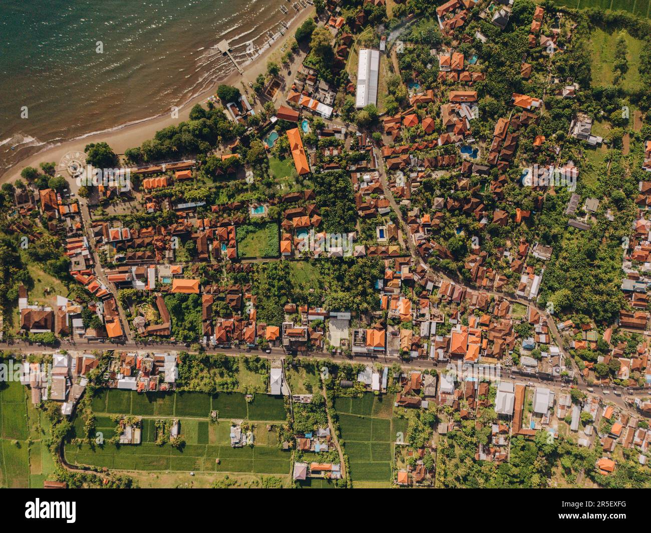 Top aerial view of pretty tropical town sits by the ocean, surrounded ...