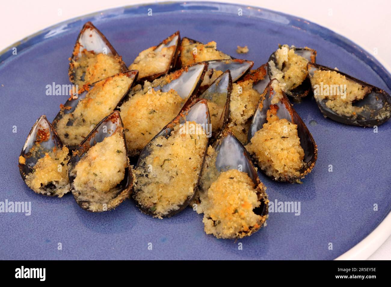 Plate of mussels au gratin. Mussels covered in wine and stuffed with ...