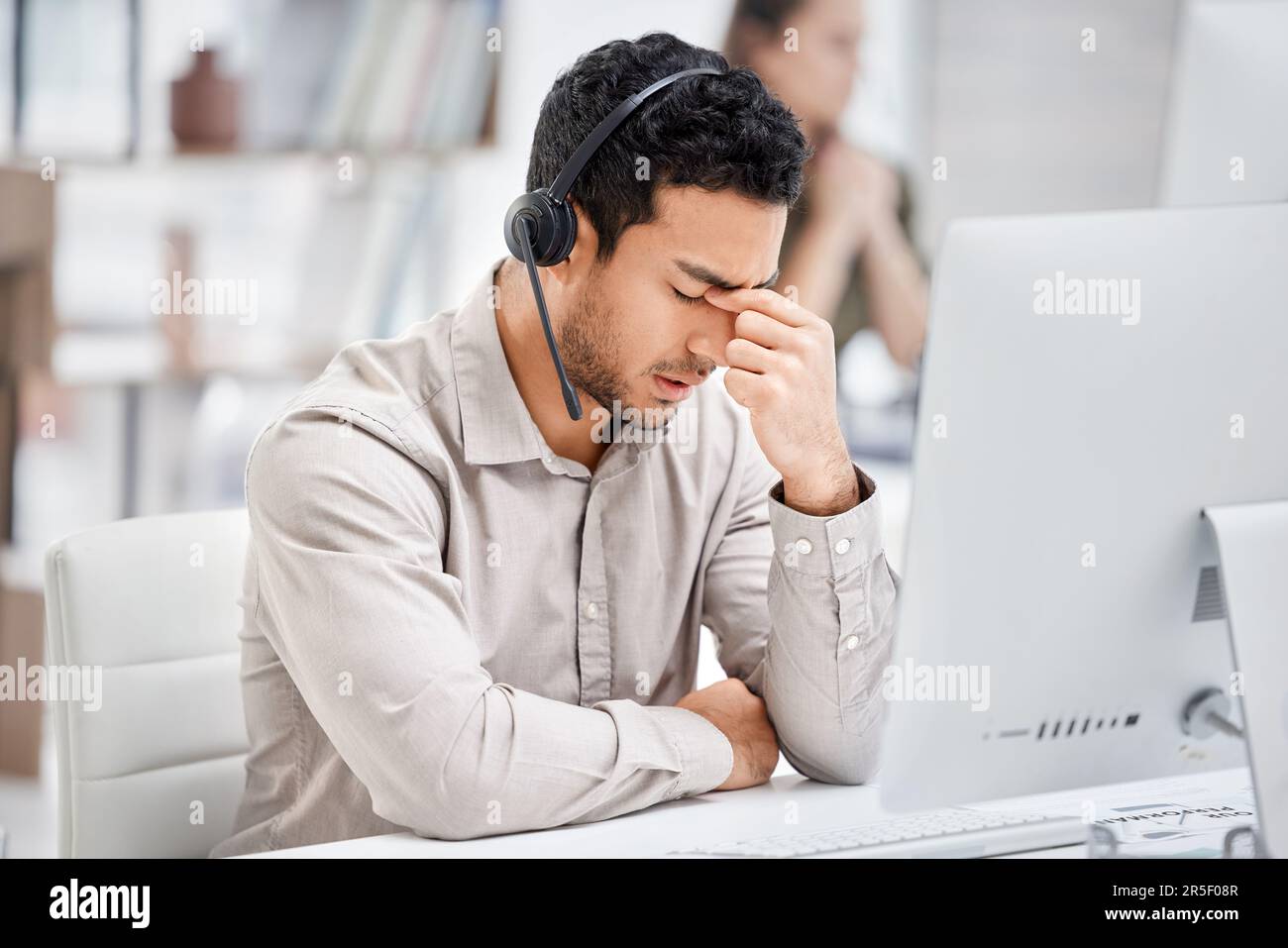 Mental health, man with headache and headset at his desk with computer ...