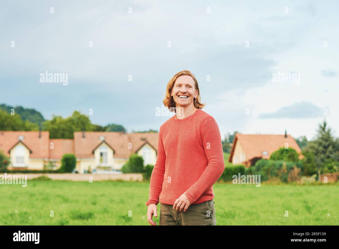 Outdoor portrait of happy male model with red hair, posing in a ...