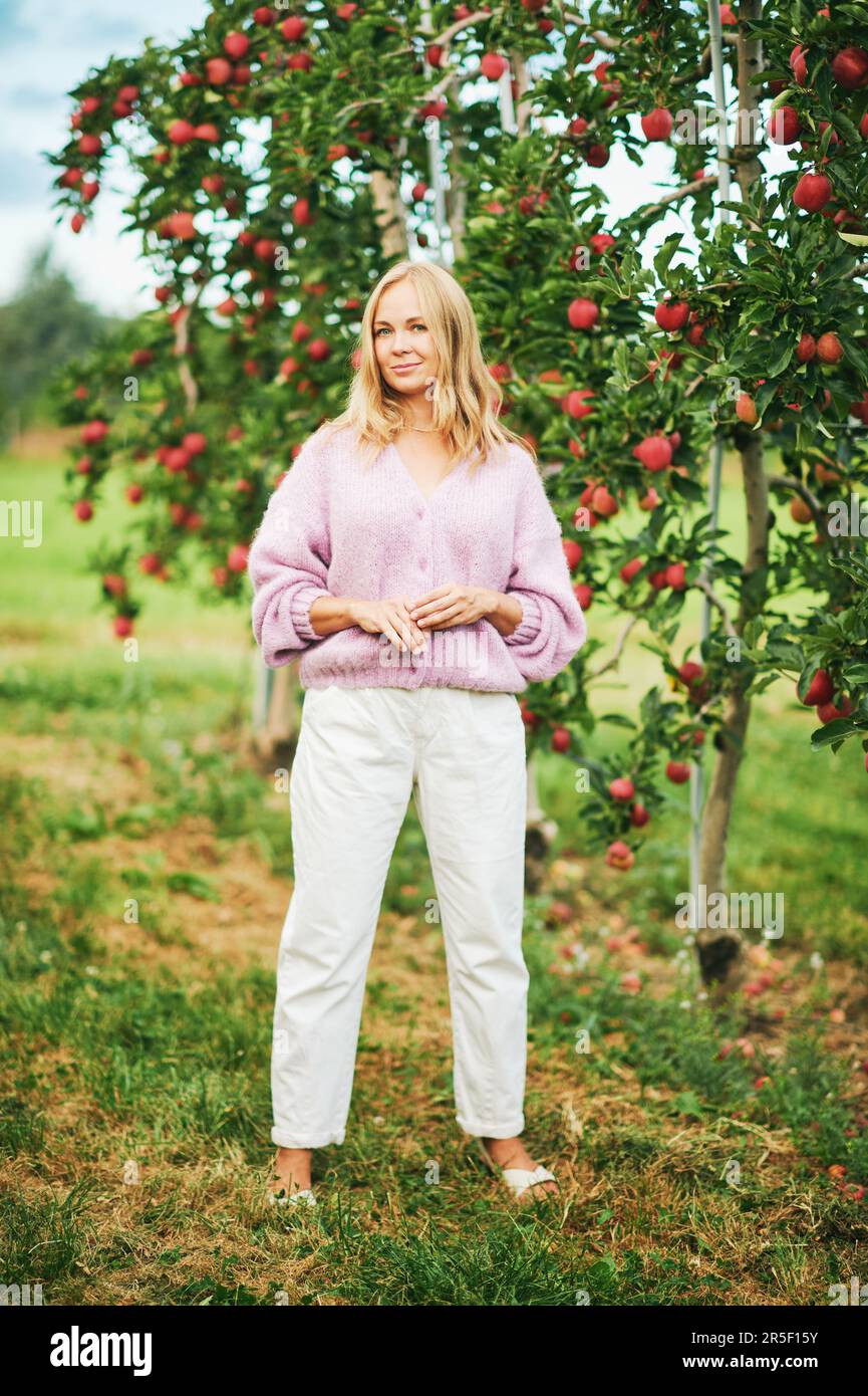 Outdoor portrait of romantic young female model posing in apple orchard ...