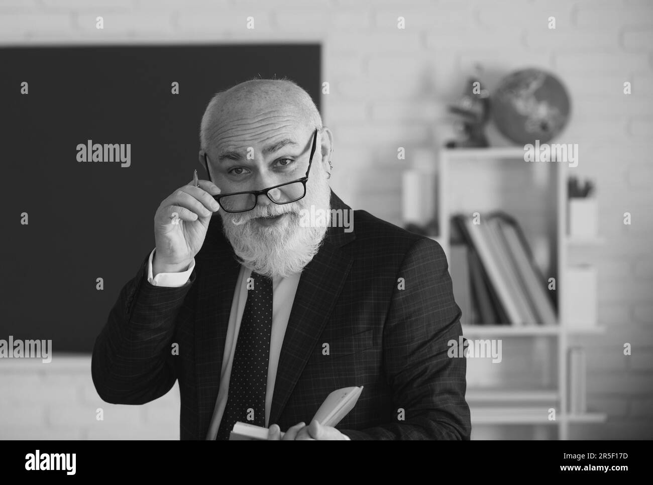 Teacher in the classroom near the blackboard is teaching a lesson ...