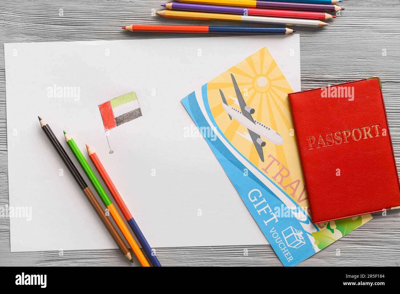Paper sheet with drawn UAE flag, pencils, gift voucher and passport on ...