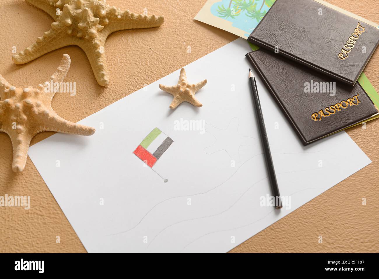 Paper sheet with drawn UAE flag, starfishes and passports on beige ...