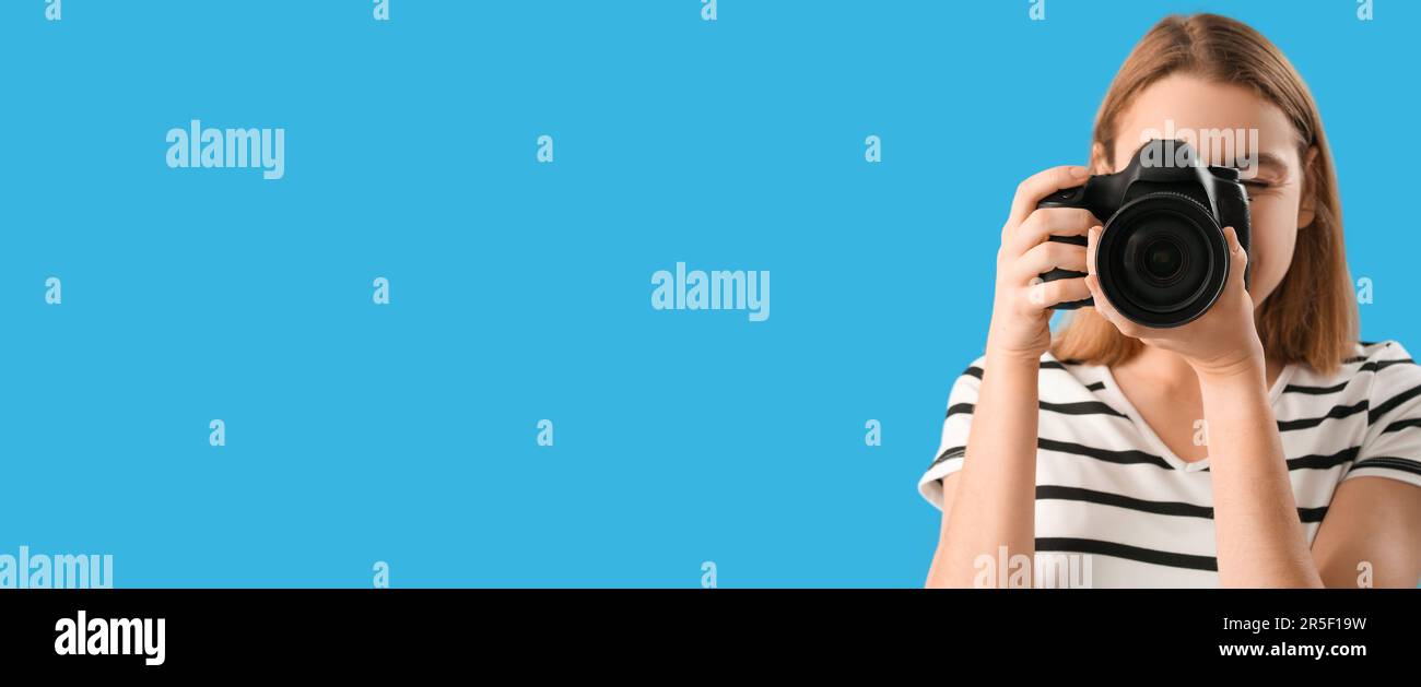 Female photographer with professional camera on light blue background ...