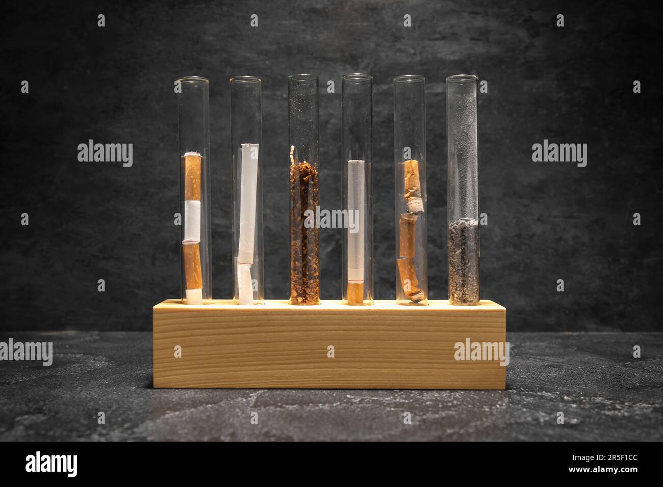 Test tubes with cigarettes and tobacco on dark background. Stop smoking ...
