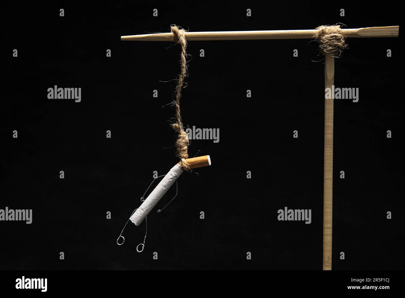 Cigarette hanging on gallows against dark background. Stop smoking ...
