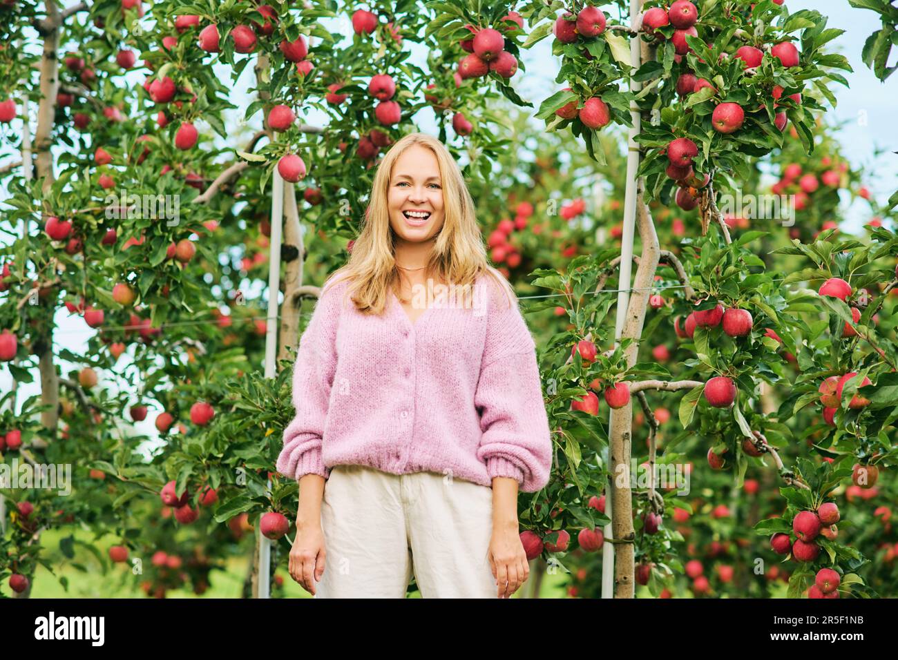 Outdoor portrait of romantic young female model posing in apple orchard ...