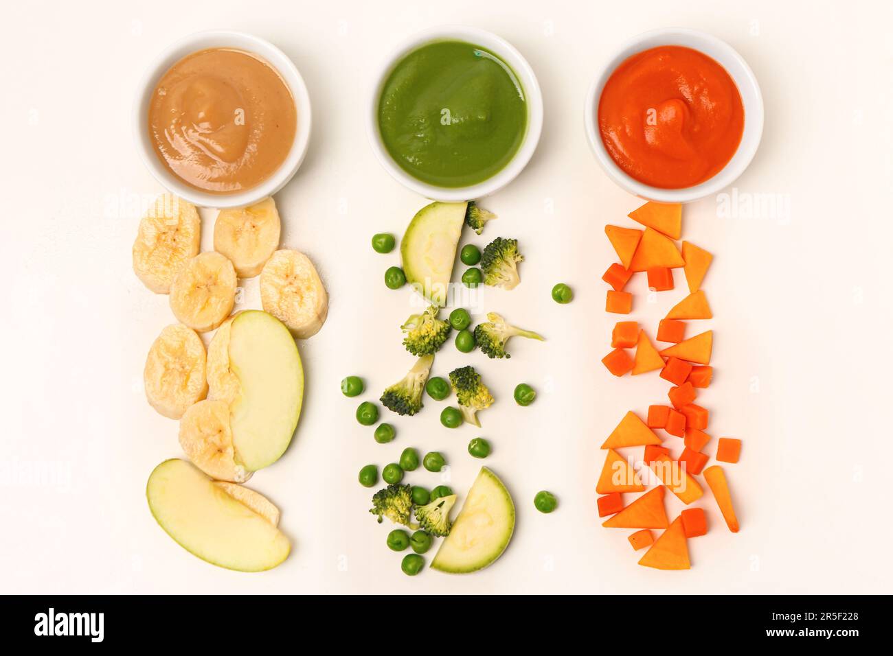 Composition with bowls of healthy baby puree and ingredients on white ...