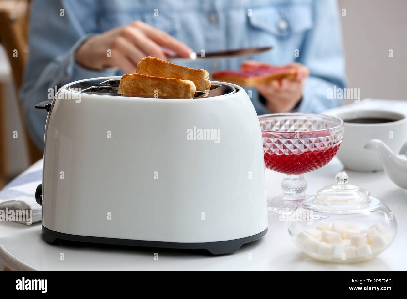Woman making delicious jam toast at table with modern toaster Stock Photo - Alamy