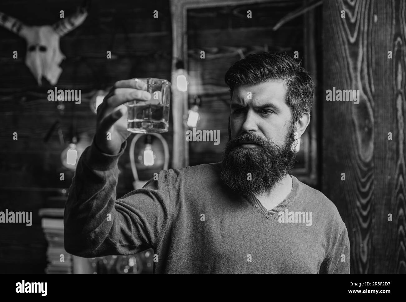 Handsome pensive man is holding a glass of whiskey. Retro bar. Man in ...