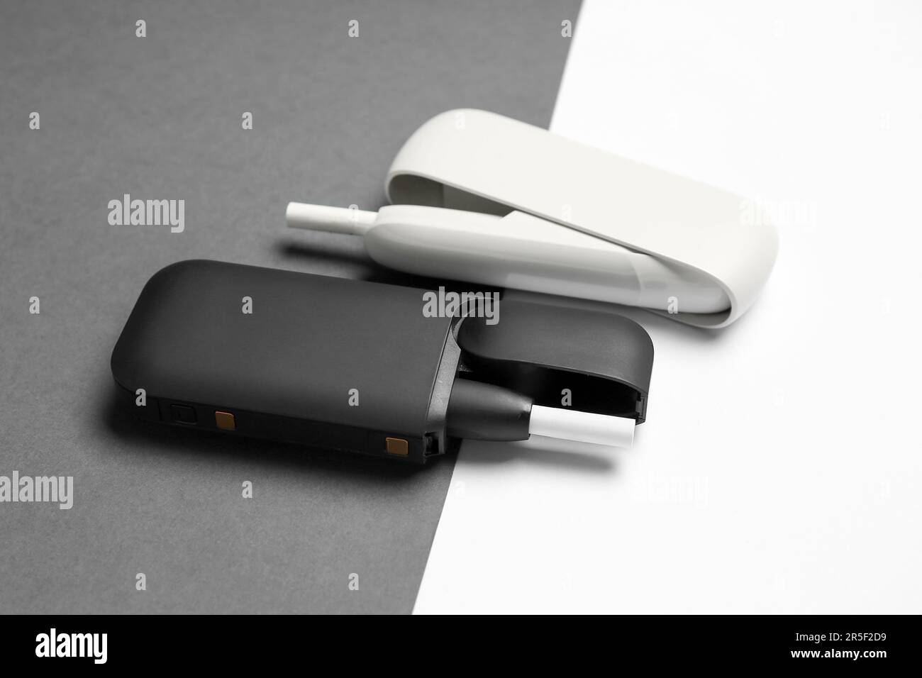 Different electronic cigars with sticks on white and black background ...