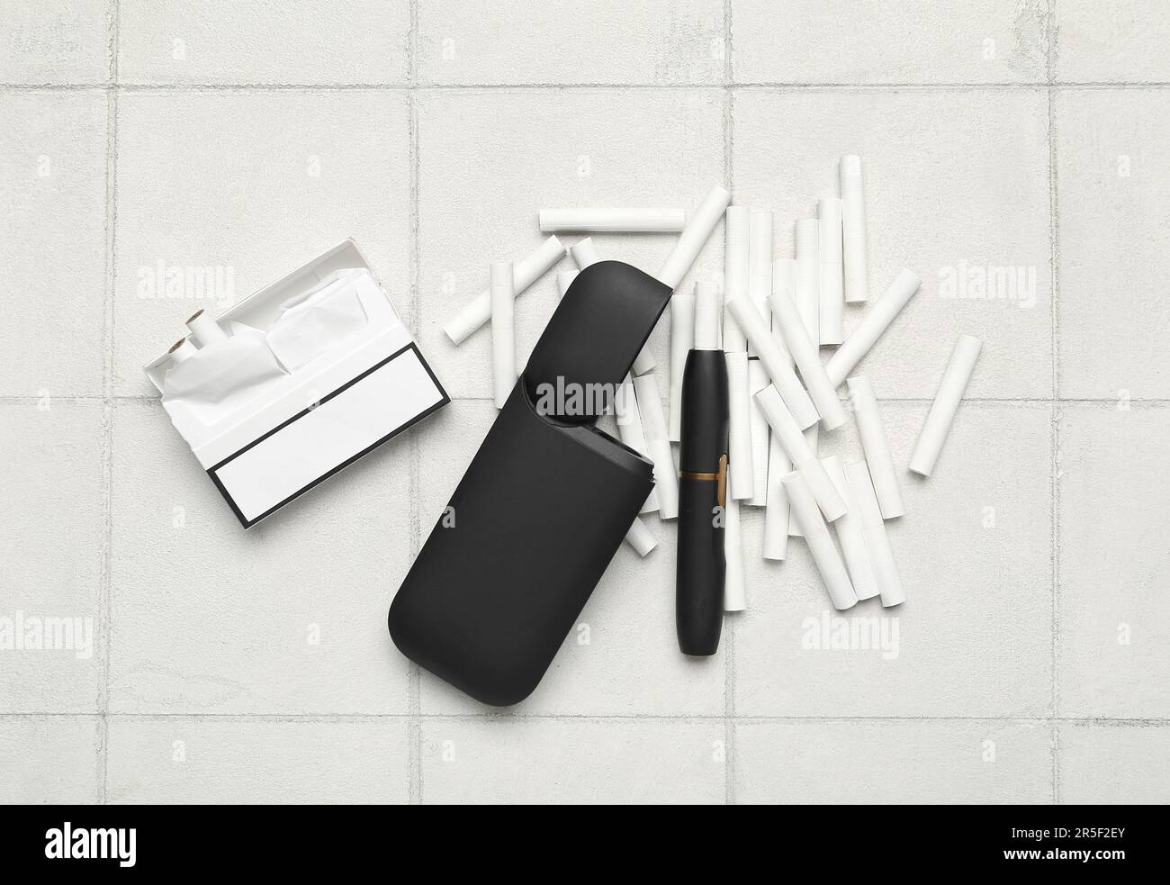 Modern electronic cigar, pack and sticks on white tiled background ...