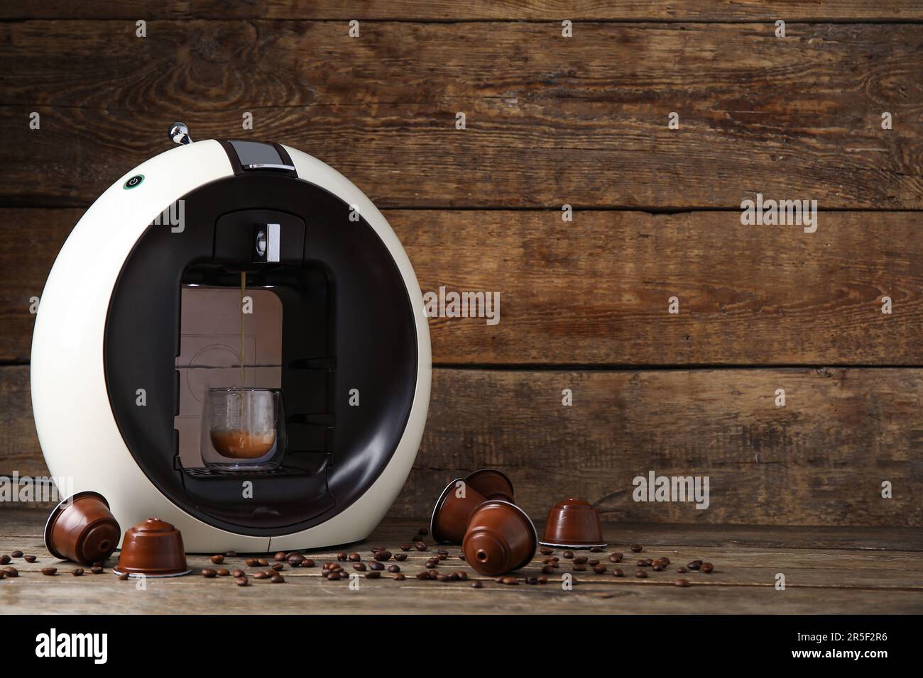 Modern capsule coffee maker with dripping espresso, glass, pods and ...