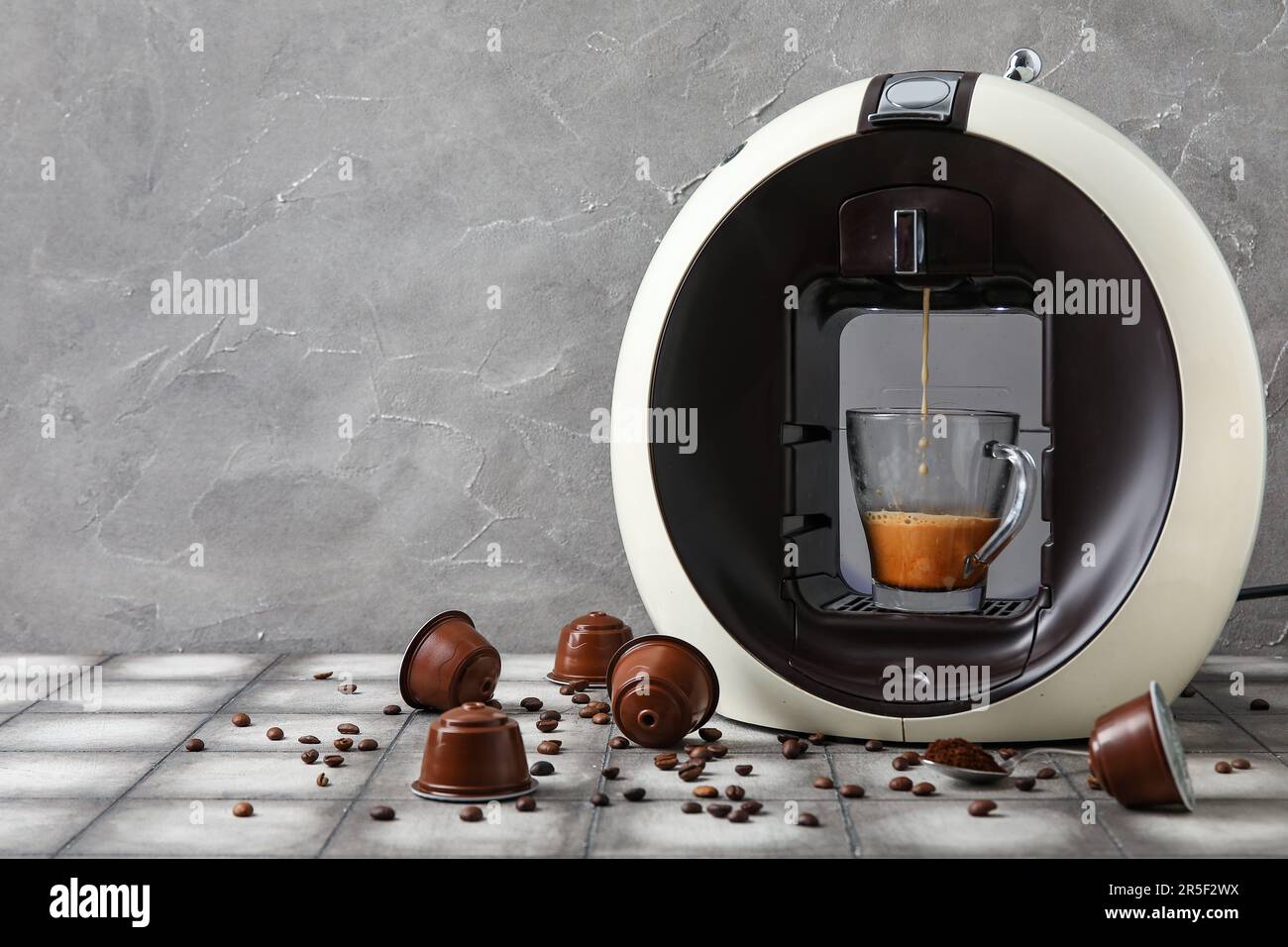 Modern capsule coffee maker with dripping espresso, cup, pods and beans ...