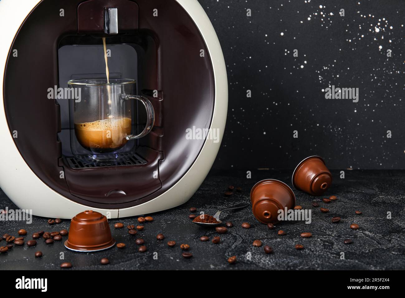 Modern capsule coffee maker with dripping espresso, cup, pods and beans ...