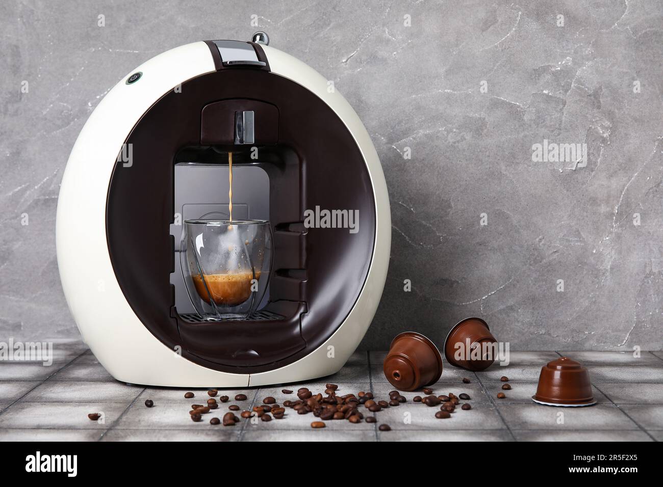 Modern capsule coffee maker with dripping espresso, cup, pods and beans ...