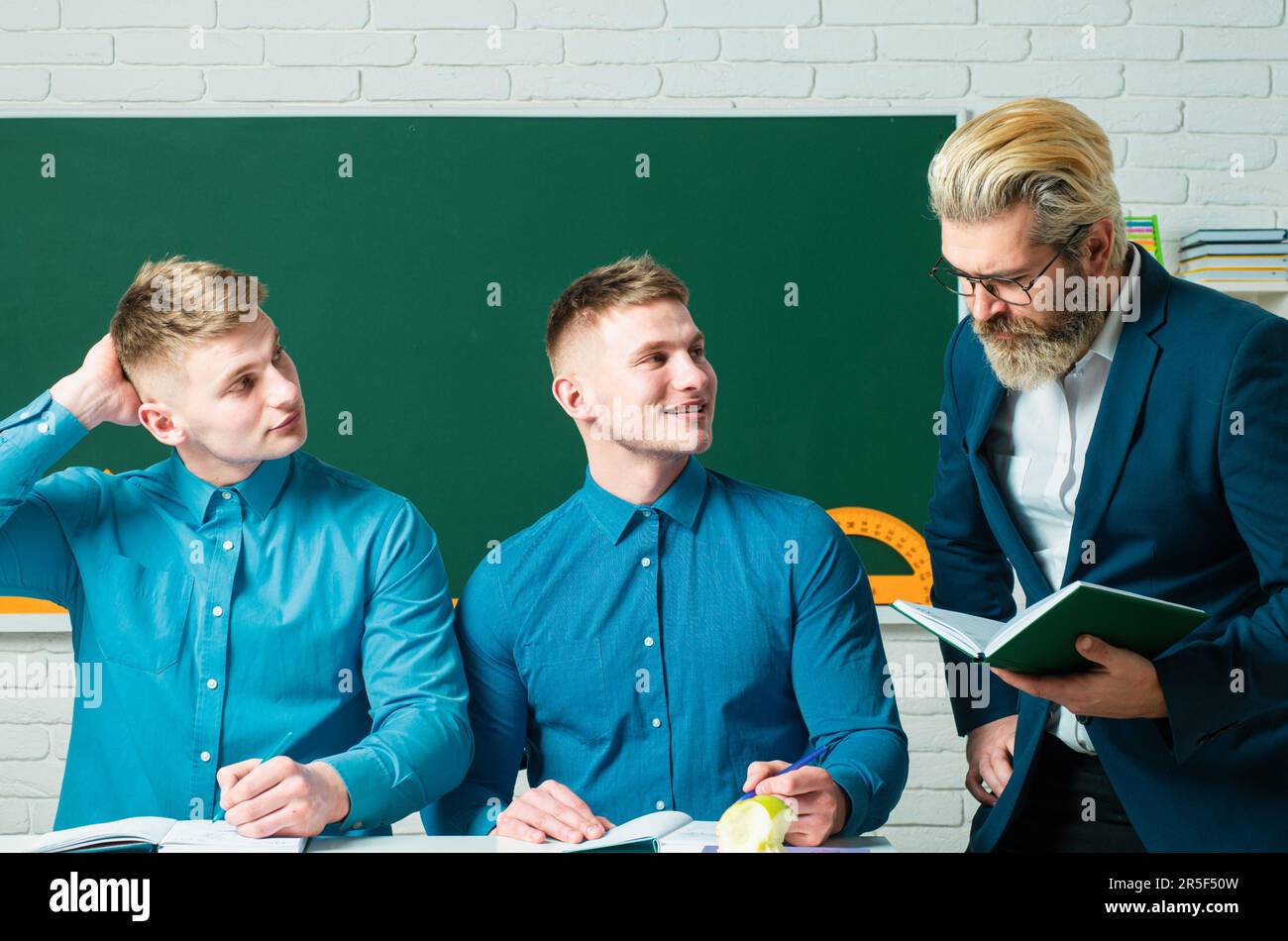 Two teenage boys twins and teacher in school dress with books. Brother ...