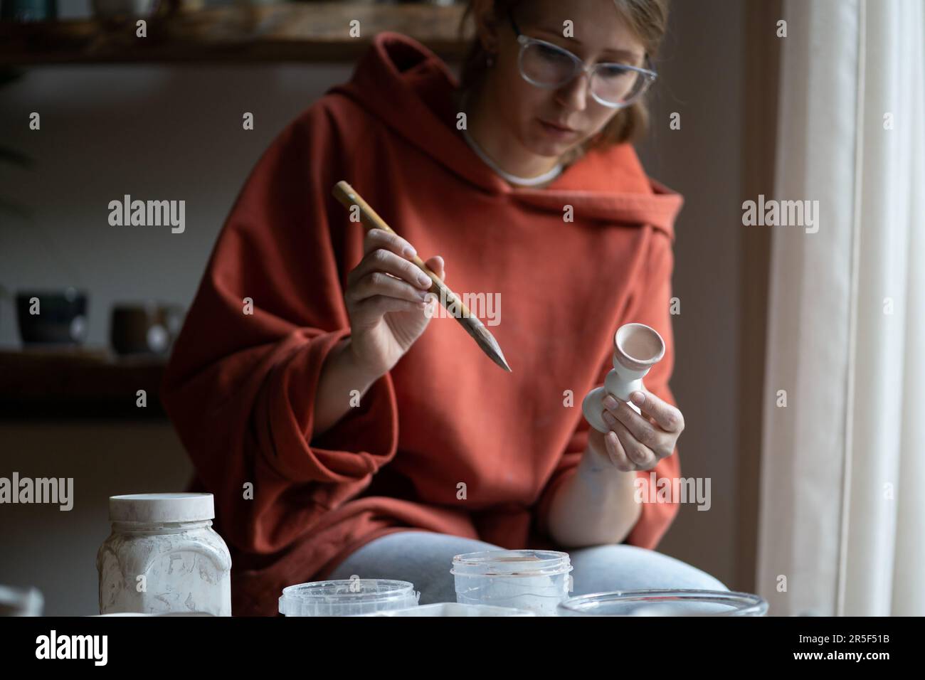 Concentrated creative woman artist enjoys making sculptures from ...