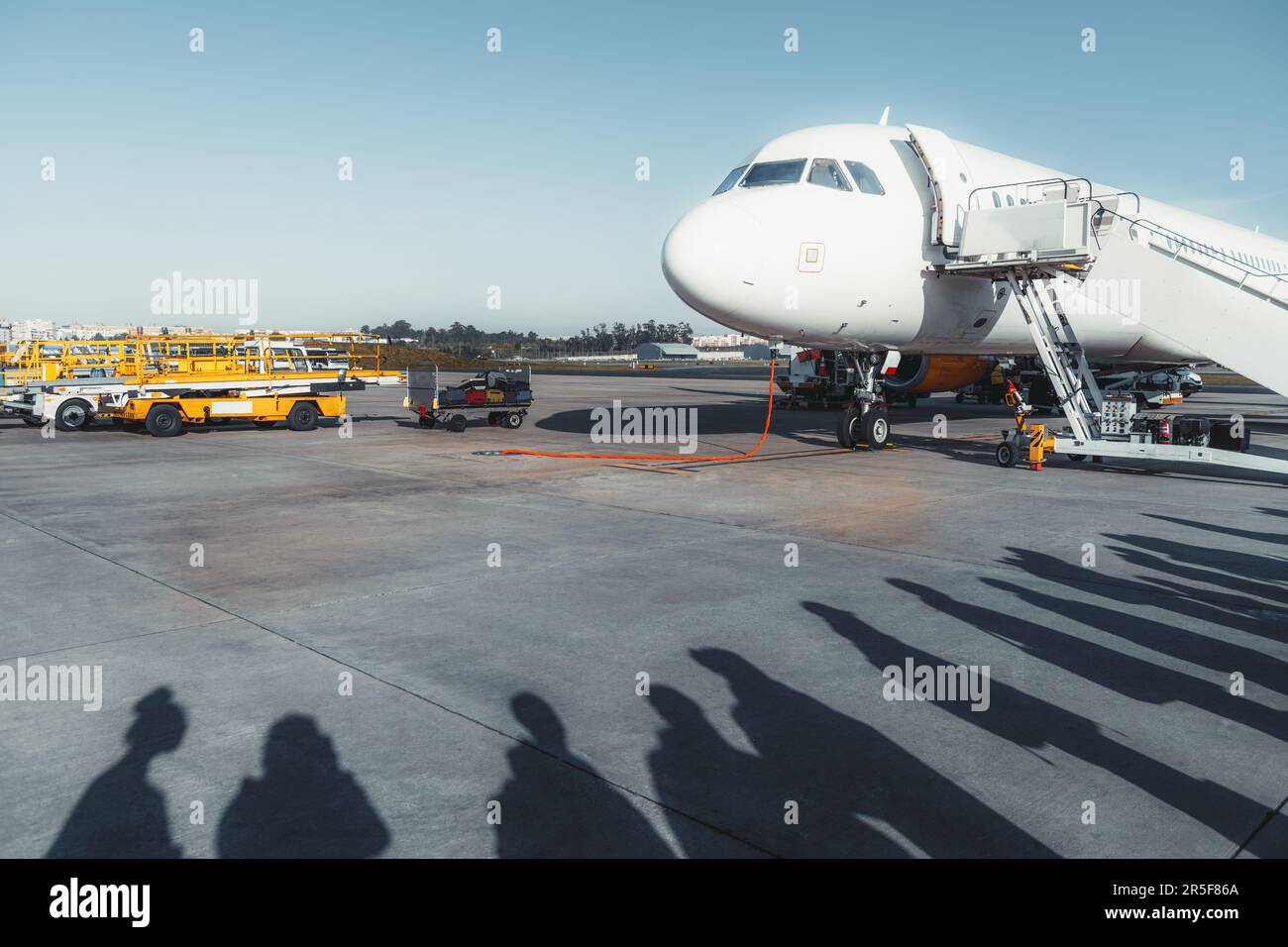 In Lisbon airport, a plane sits on the right side with stairs. Shadows ...