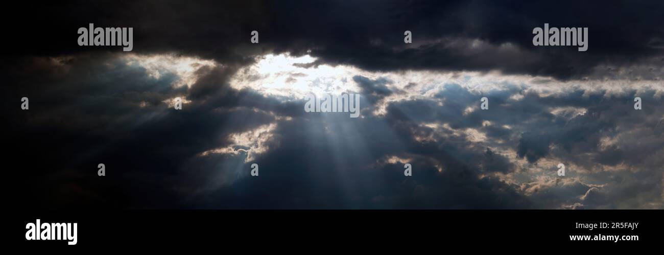 A panoramic view of a dramatic sky with rays of sunlight breaking ...