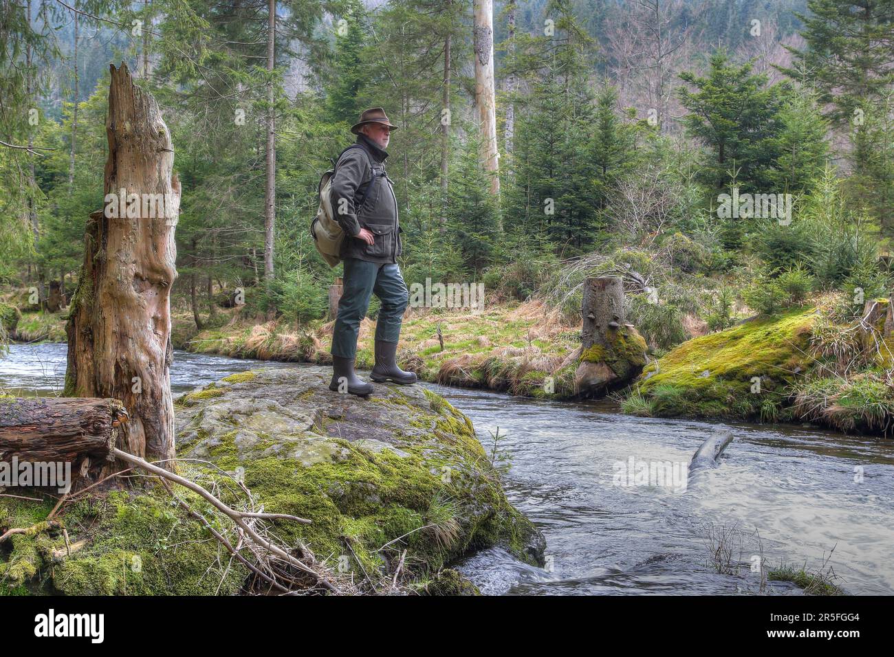 A wanderer stands on a ledge above a wild river that flows under him ...