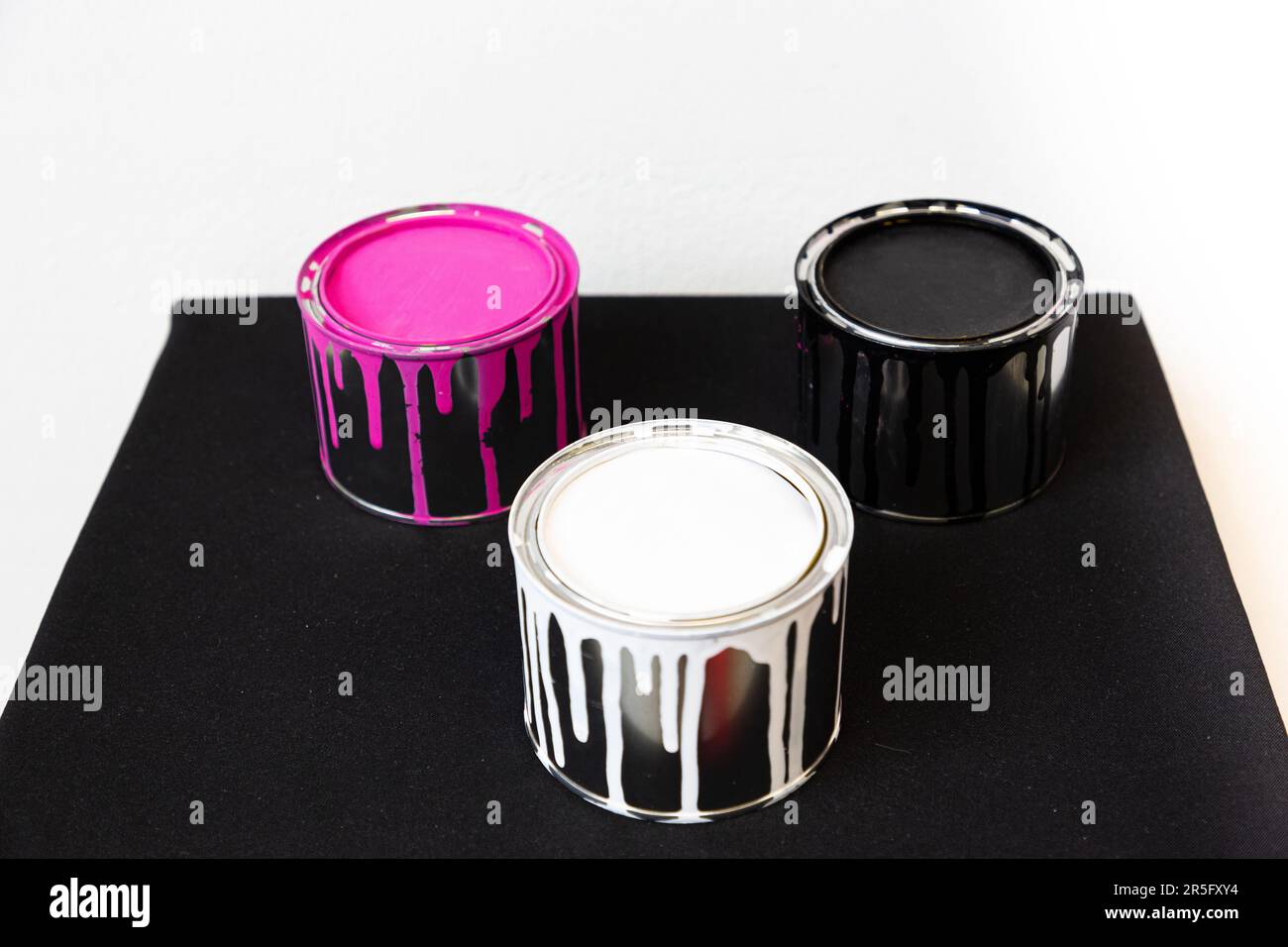Three paint cans of white, pink and black paint form a triangle on a ...