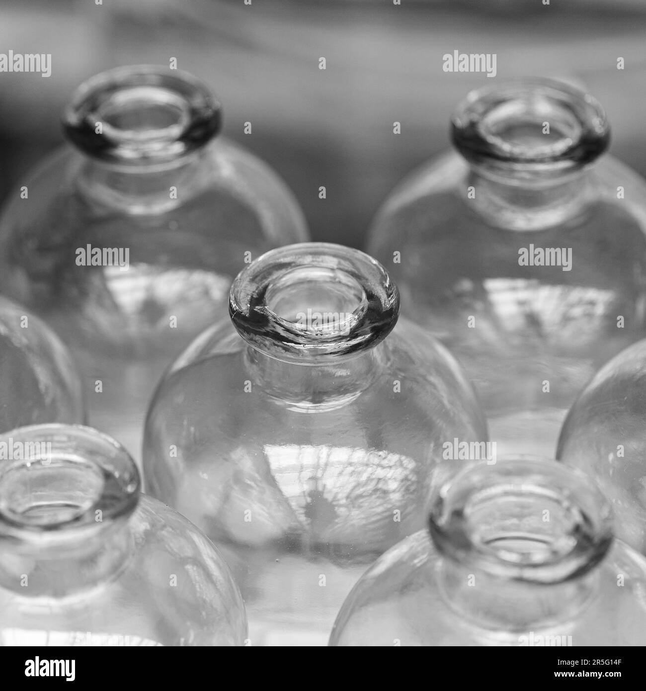 Bottles with a thick rim on the neck stand in rows behind and next to ...