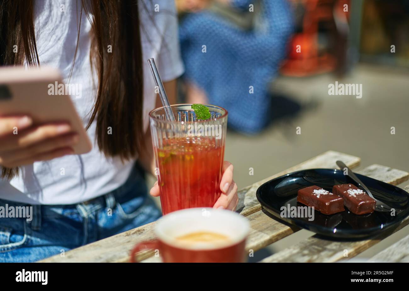Young girl drinking strawberry mojito in a outdoor cafe. Unrecognizable ...