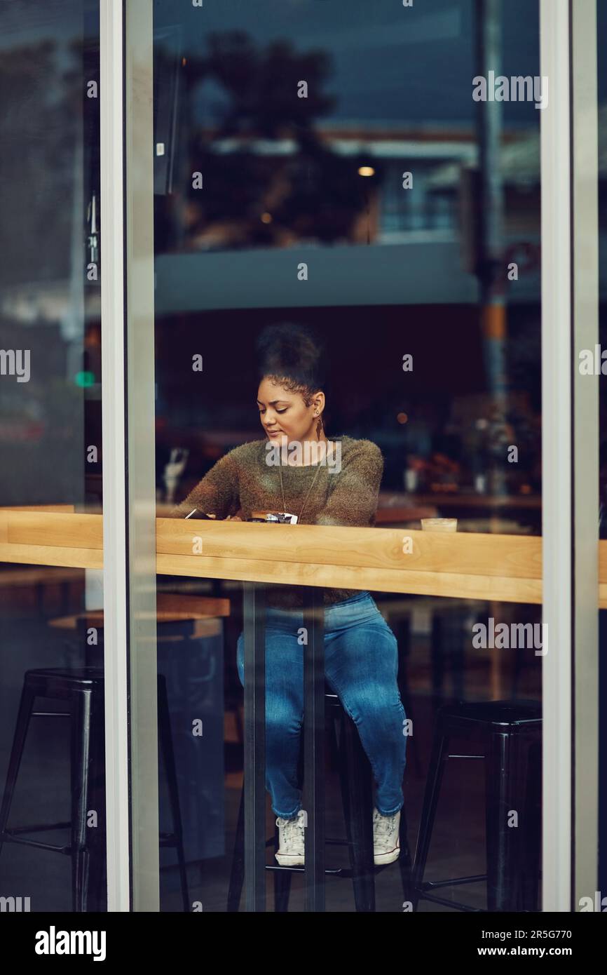 Chilling at her favourite cafe. an attractive young woman sitting in a ...