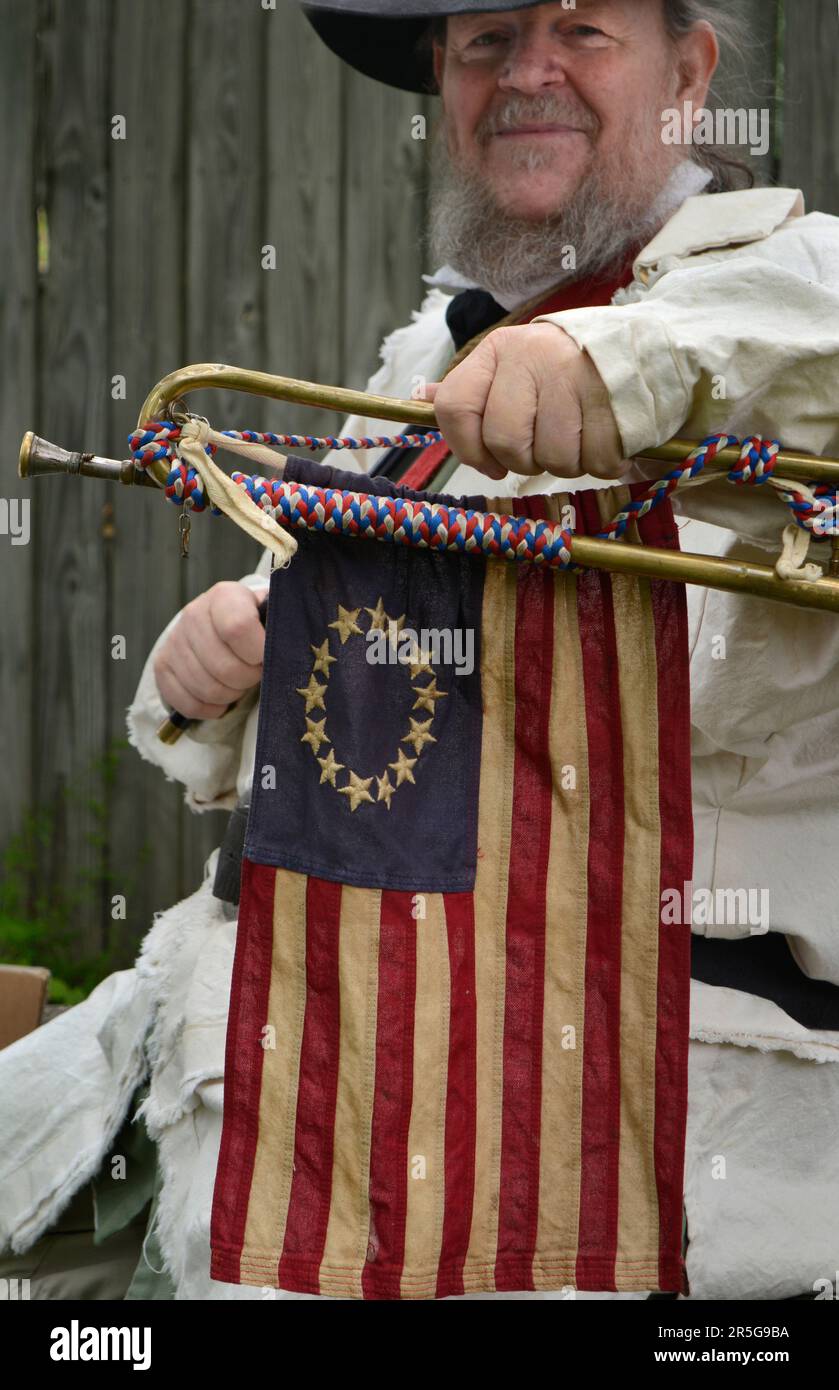An American history reenactor plays and holds a trumpet embellished ...
