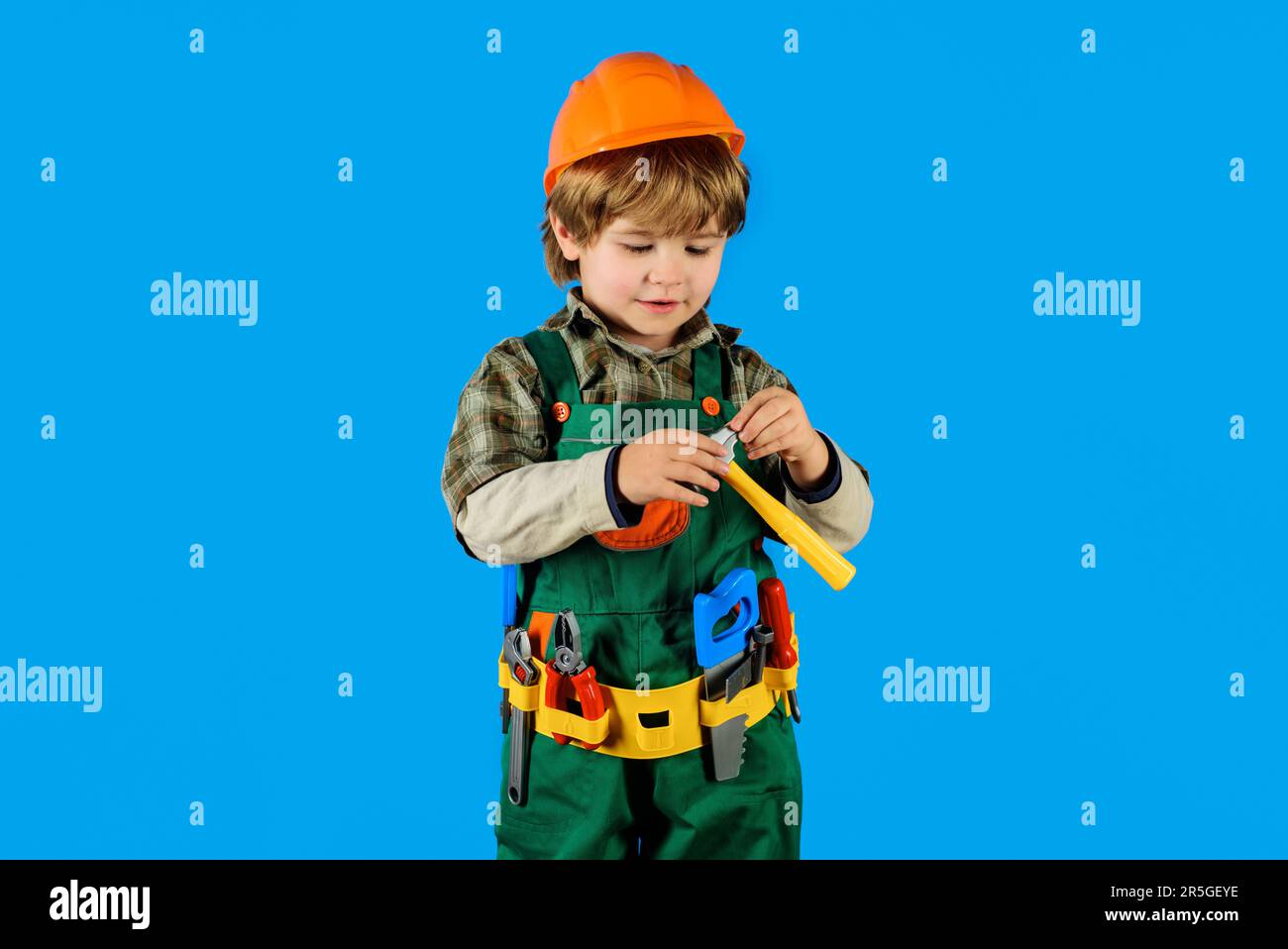 Child boy in helmet and toolbelt with hammer. Little repairman or ...