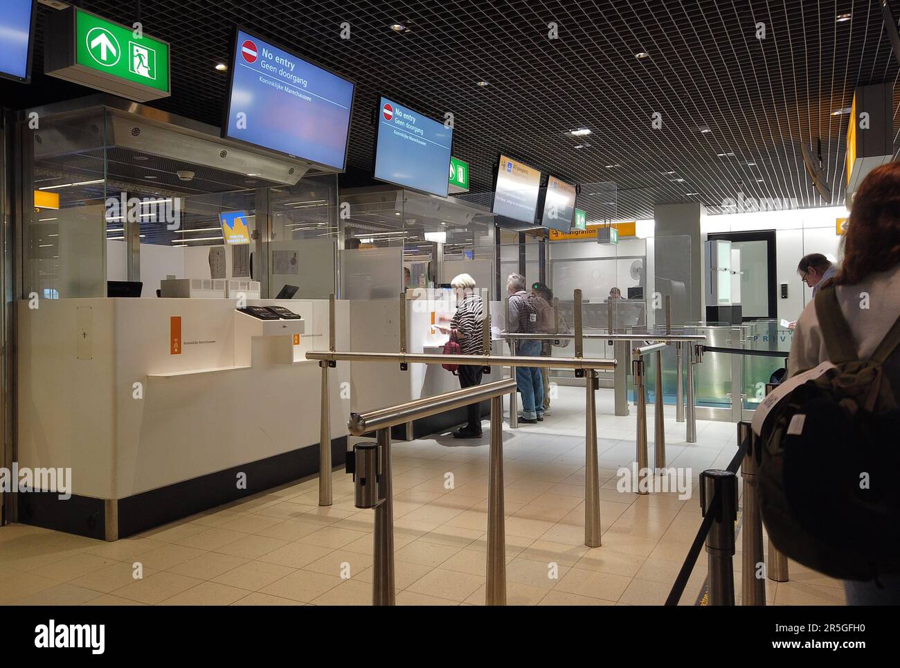 Passengers go through passport control booth in Schiphol airport in ...