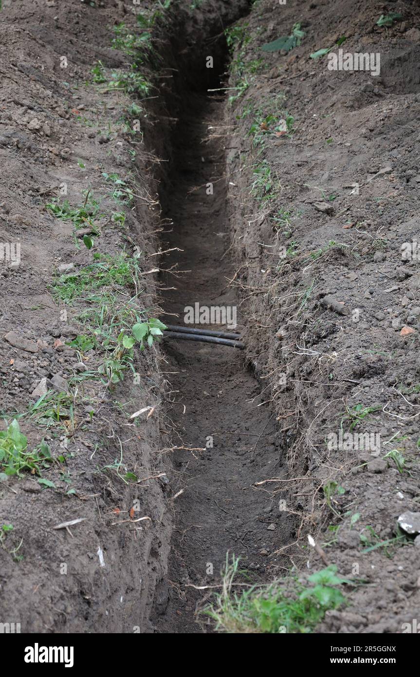 Trench in ground for laying utility lines Stock Photo - Alamy