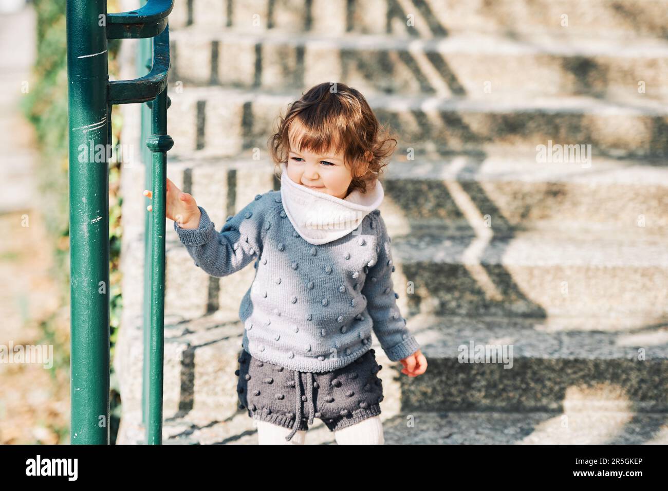 Outdoor portrait of adorable toddler girl walking up the stairs, child ...