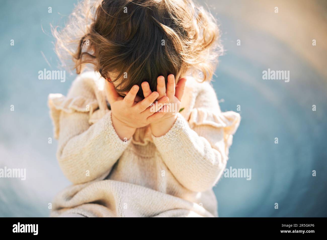 Portrait of adorable little girl hiding face with hands Stock Photo - Alamy