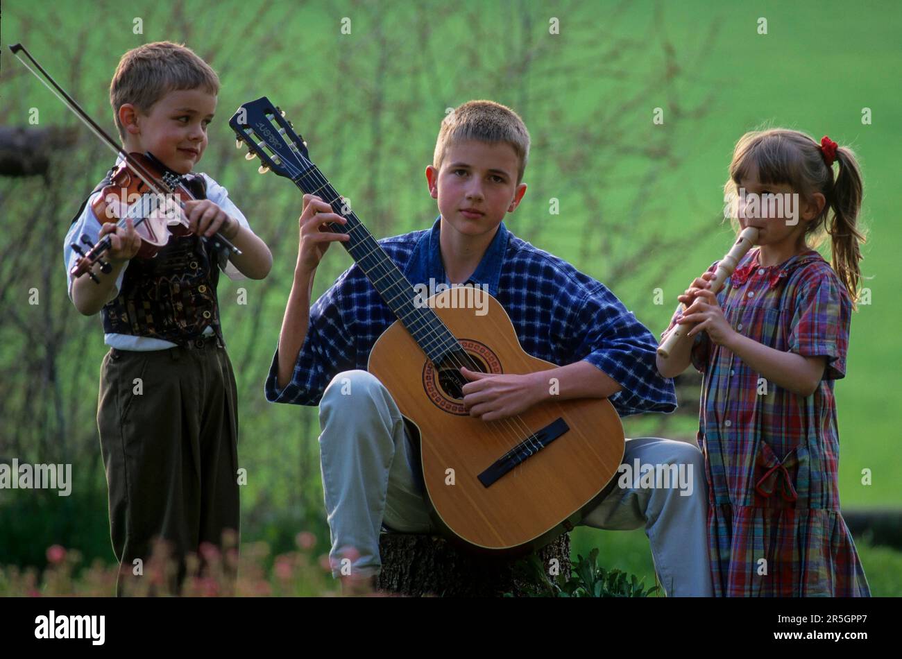 Three 3 children play music in the group, flute, guitar and violin ...