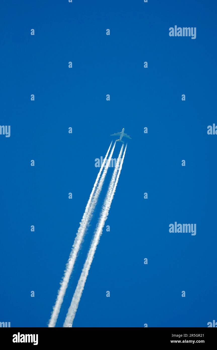 Four-engine jet with condensation trails in the blue sky Stock Photo ...