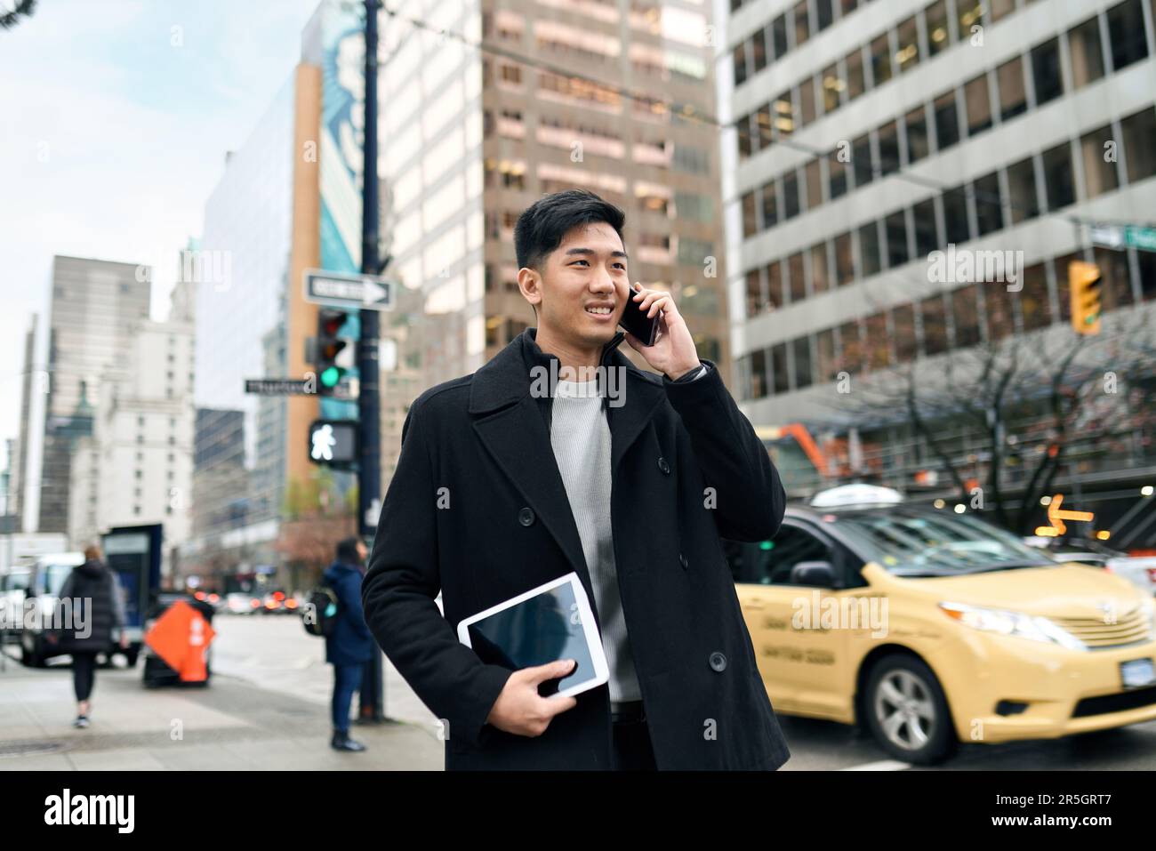 Young busy happy Asian business man walking on city street making phone ...