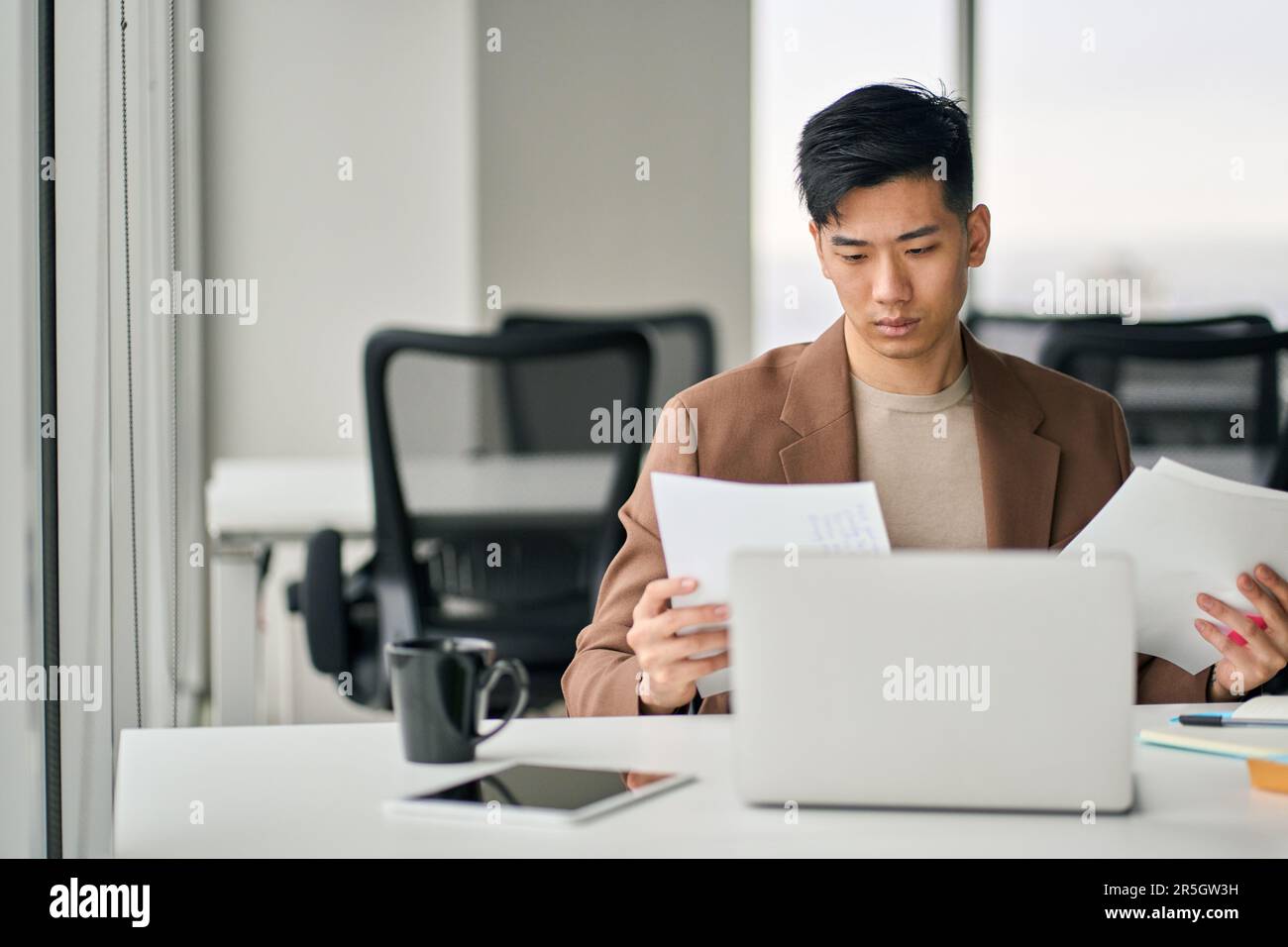 Serious Asian business man checking corporate financial documents in ...