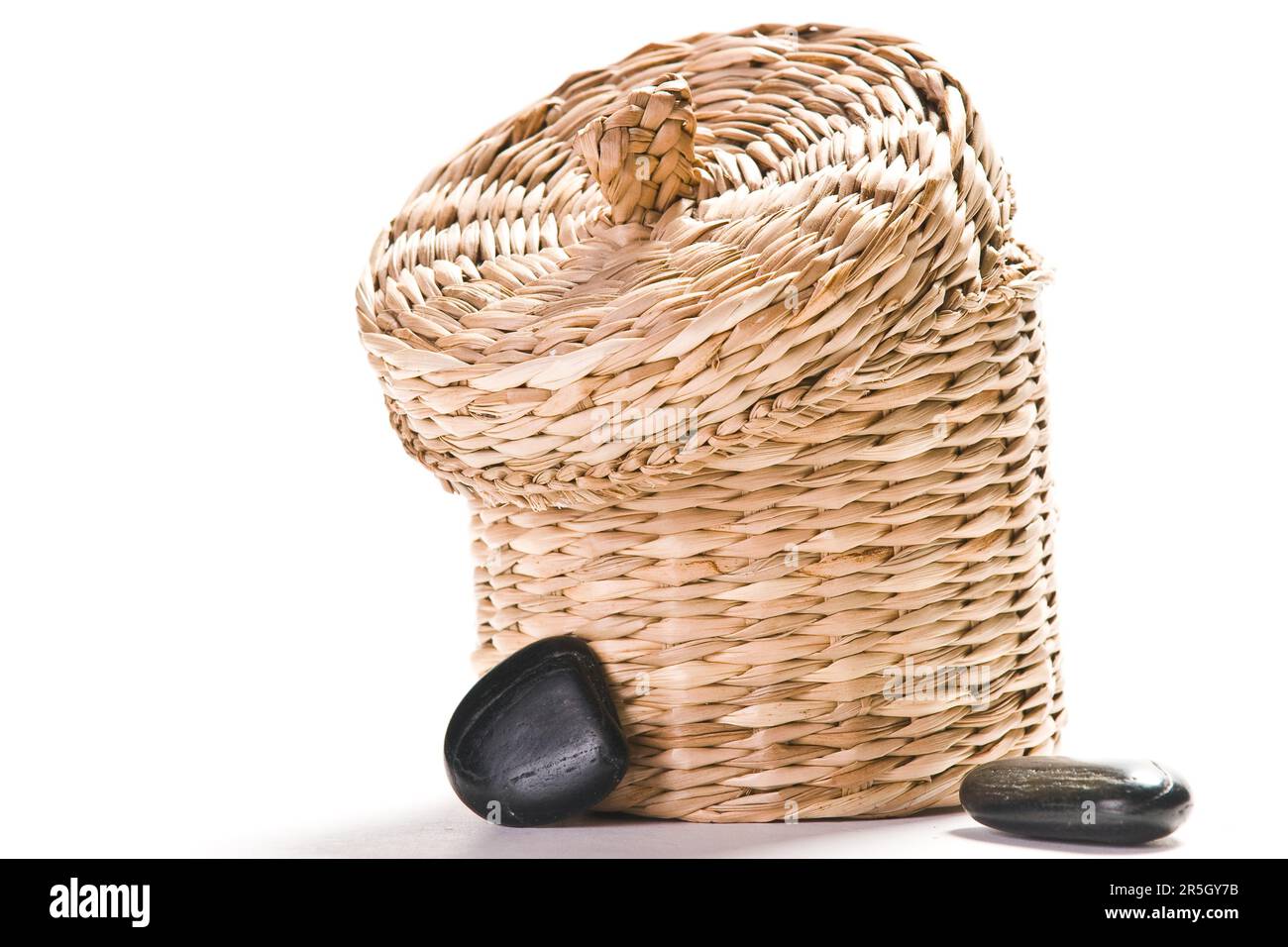 Brown basket with stones against a white background Stock Photo - Alamy