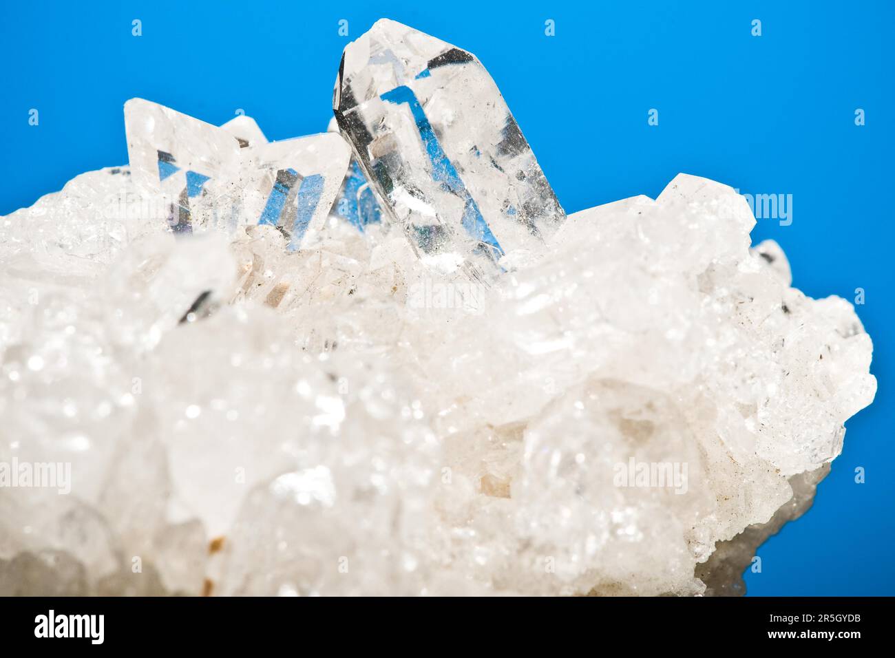 White luminous mountain crystal quartz with blue background Stock Photo ...