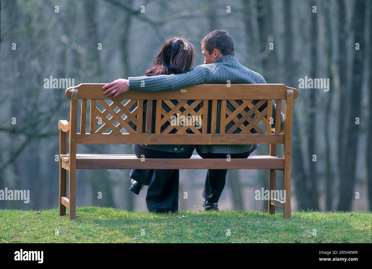 Couple sitting on park bench Stock Photo - Alamy